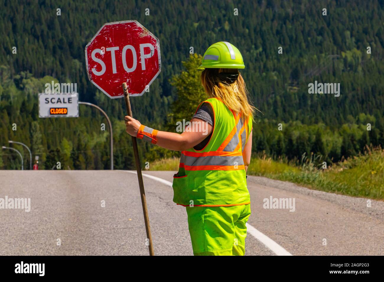 A close up and rear view of a female road construction worker holding a ...