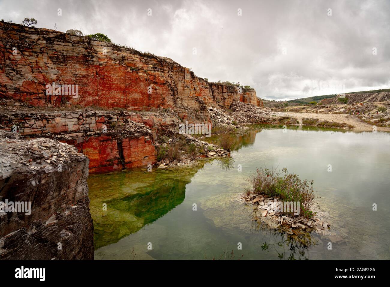 A former quarry with red layers of rocks and green water in Minas ...