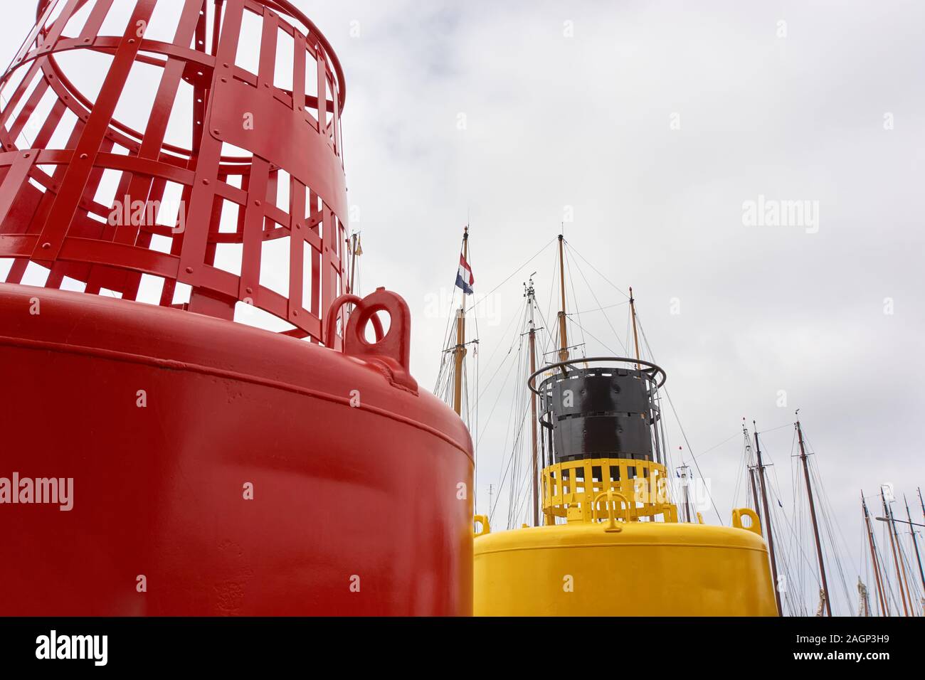 Large red and yellow buoy in front of multiple masts with a dutch flag ...