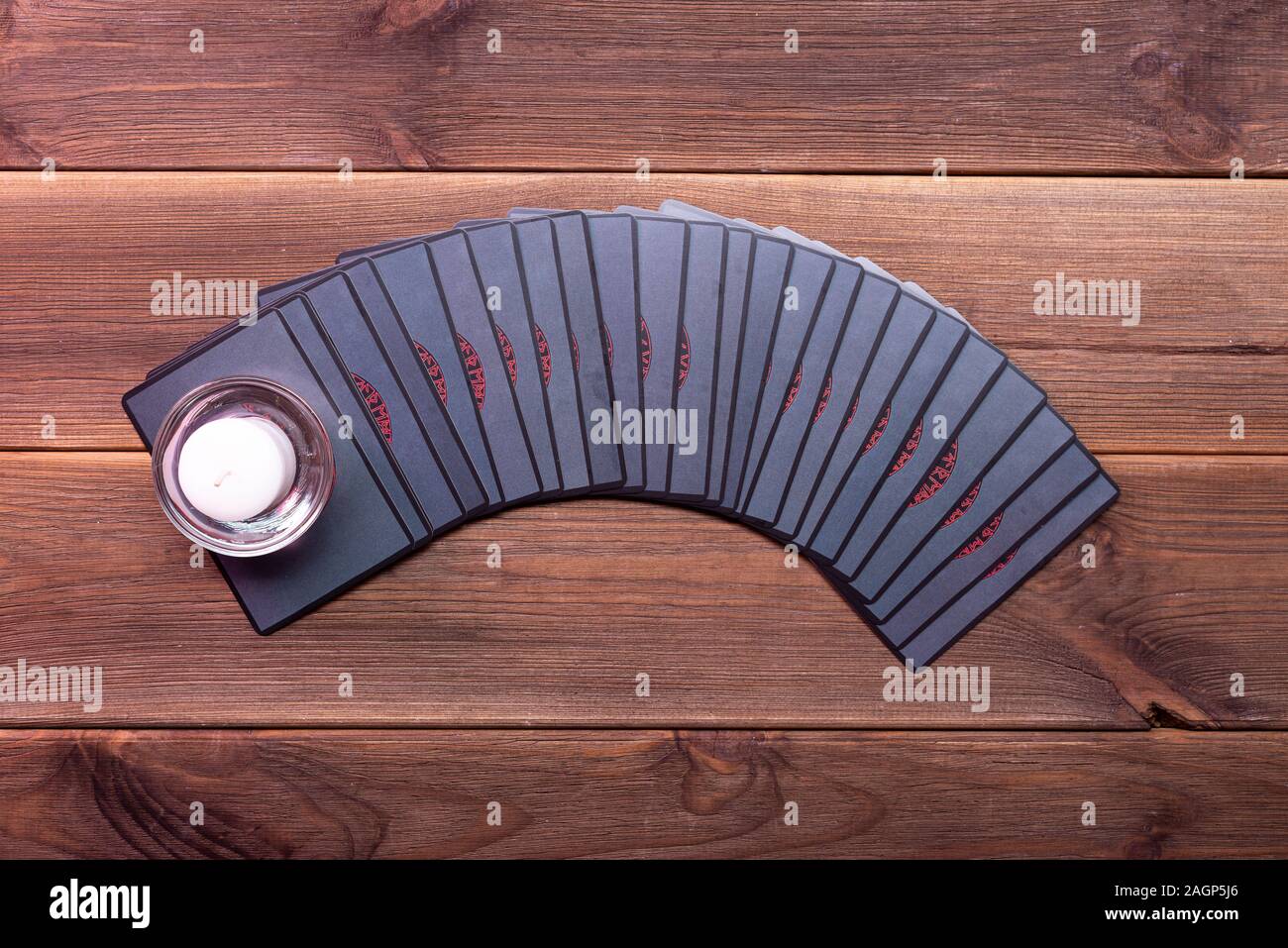 Fortune telling cards on a wooden table with a candle. Top view, place ...