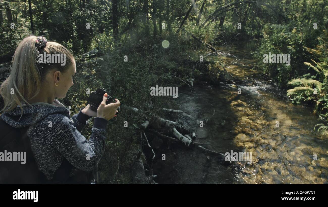 Traveler photographing scenic view in forest river. Wood bridge fallen ...