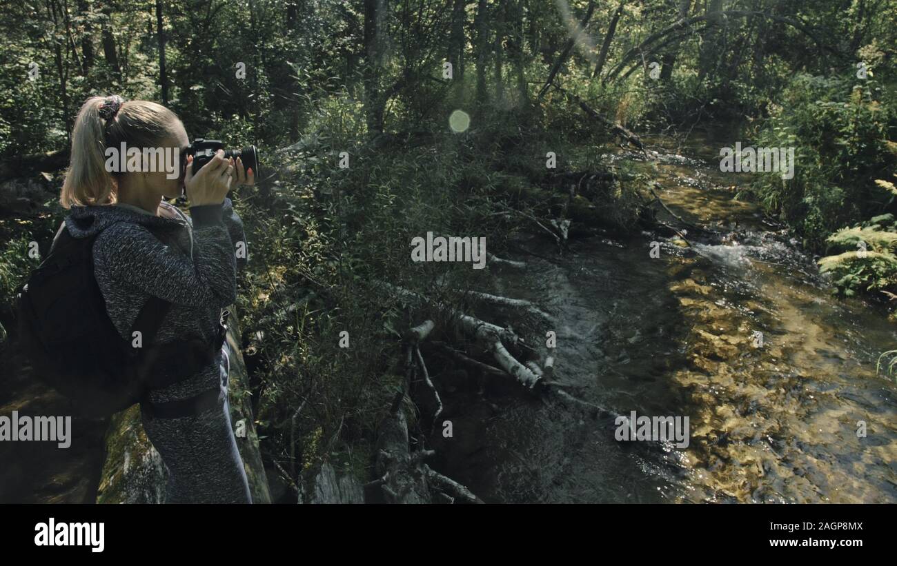 Traveler photographing scenic view in forest river. Wood bridge fallen ...