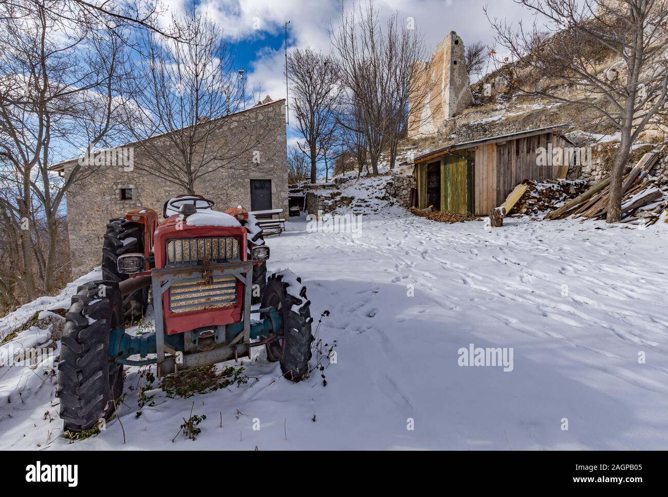 Rural mountain scene of an old tractor parked in a snowy courtyard on a ...