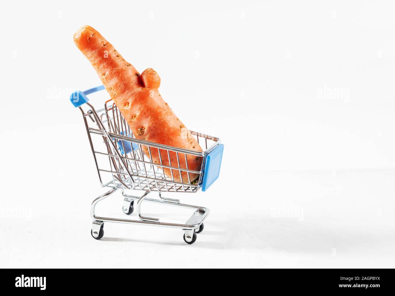 Trendy ugly food concept. Funny carrot in toy grocery cart on white ...