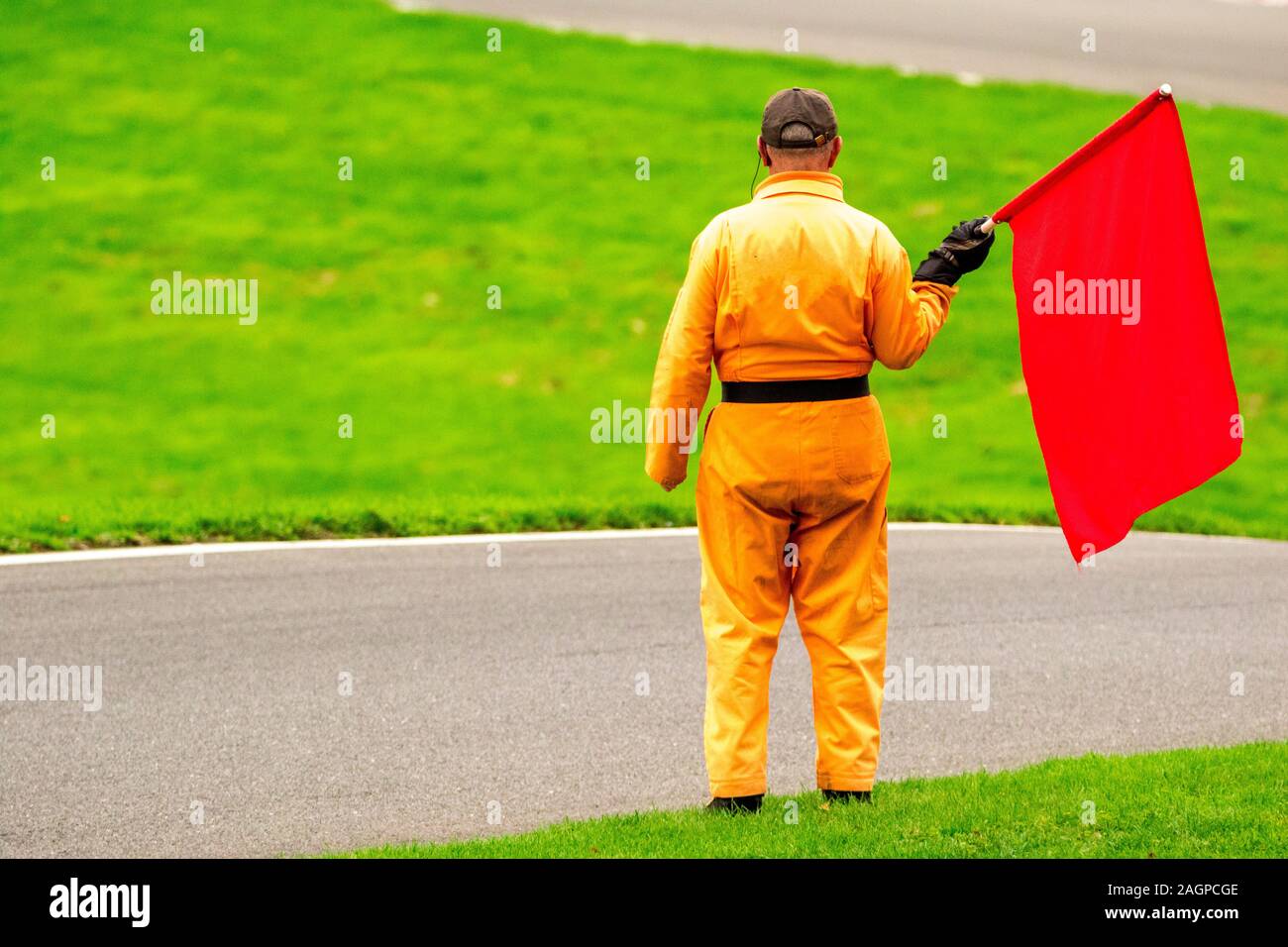 A marshal at a racetrack holds up a red flag to the rider(s Stock Photo ...