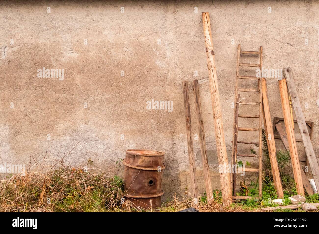 Various farm shed tools and equipment lay against an old farm shed ...