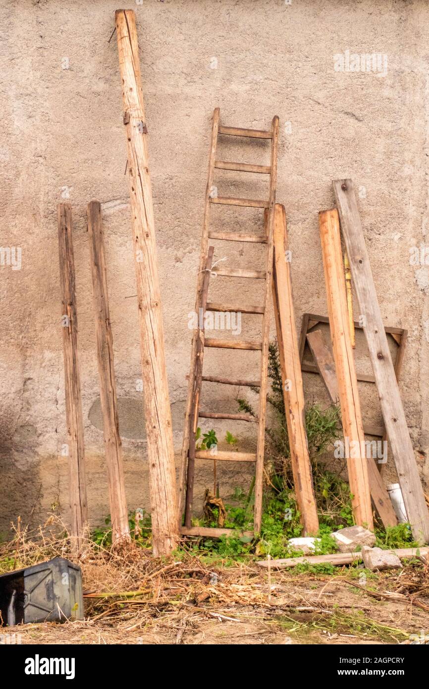 Various farm shed tools and equipment lay against an old farm shed ...