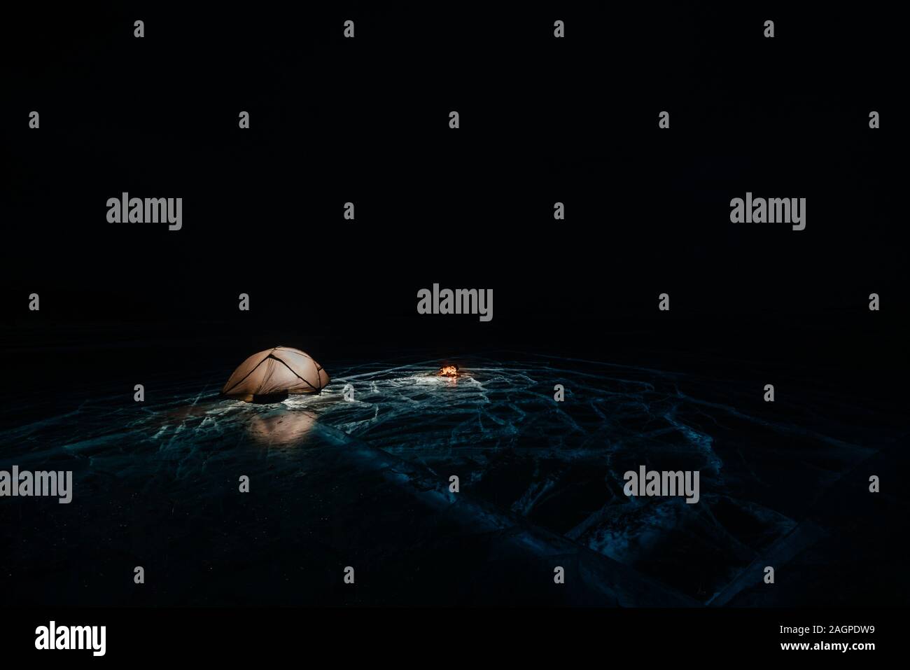 Fire on ice at night. Campground on ice. Tent stands next to bonfire ...