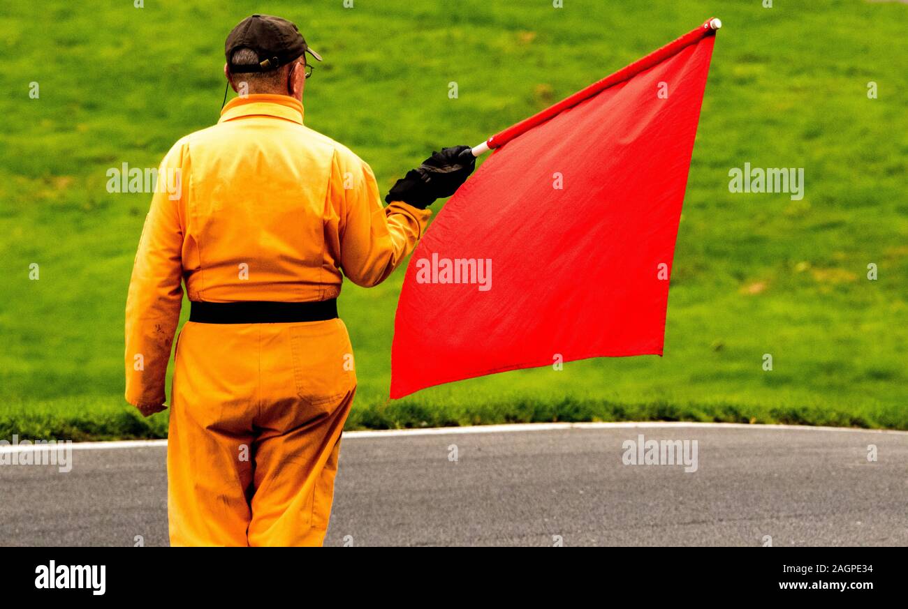A marshal at a racetrack holds up a red flag to the rider(s Stock Photo ...