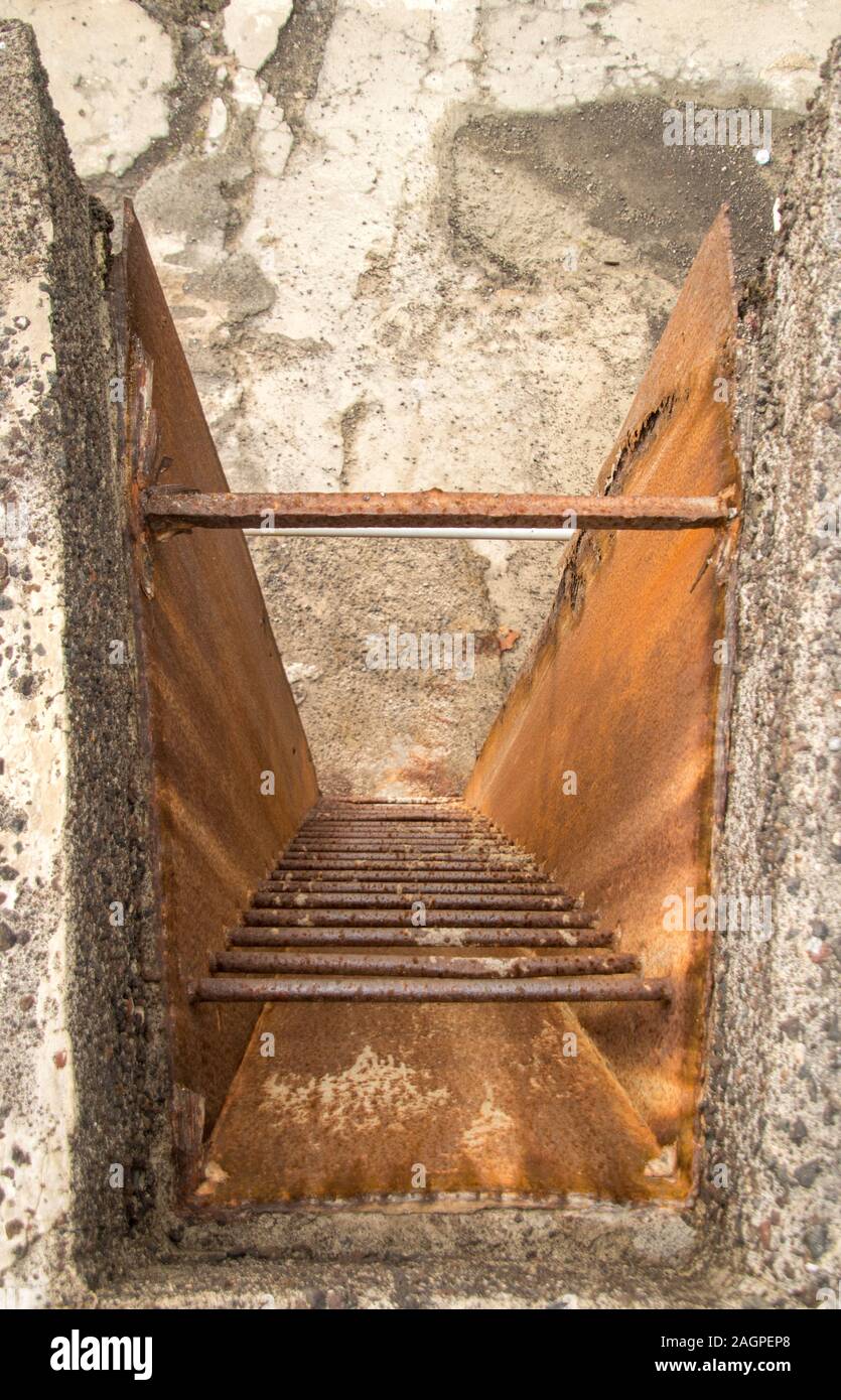 A metal set of steps, on a harbour wall, seen from the top of the climb ...