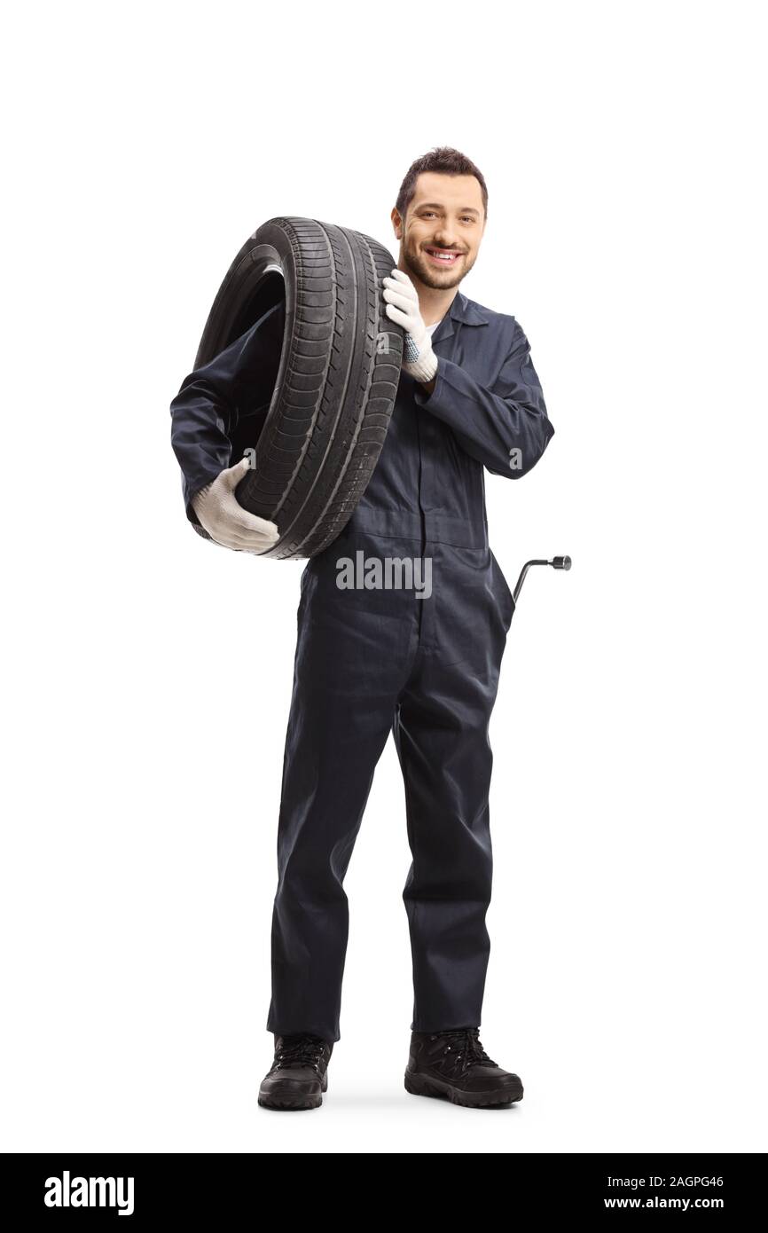 Full length portrait of an auto mechanic carrying a tire and smiling at ...