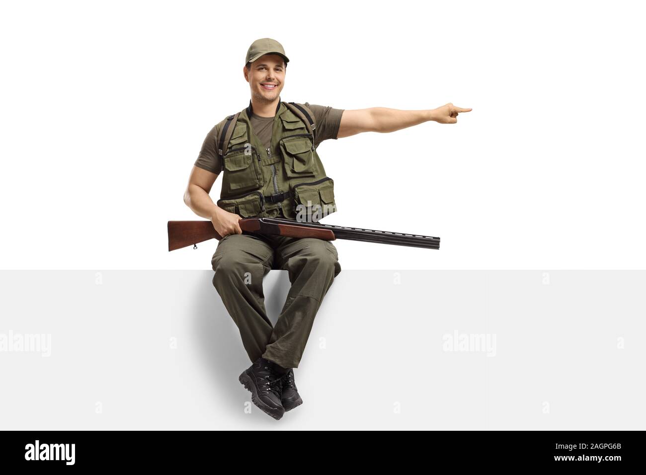 Male hunter with equipment sitting on a panel and pointing to the side ...