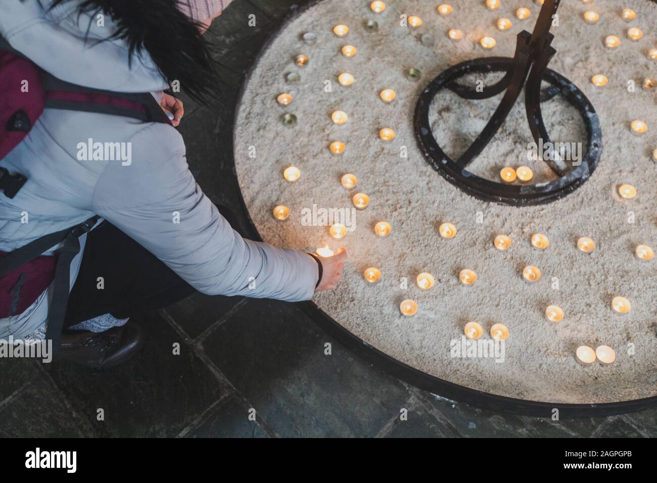 Traveling woman adding a lighted tealight prayer candle in the church ...