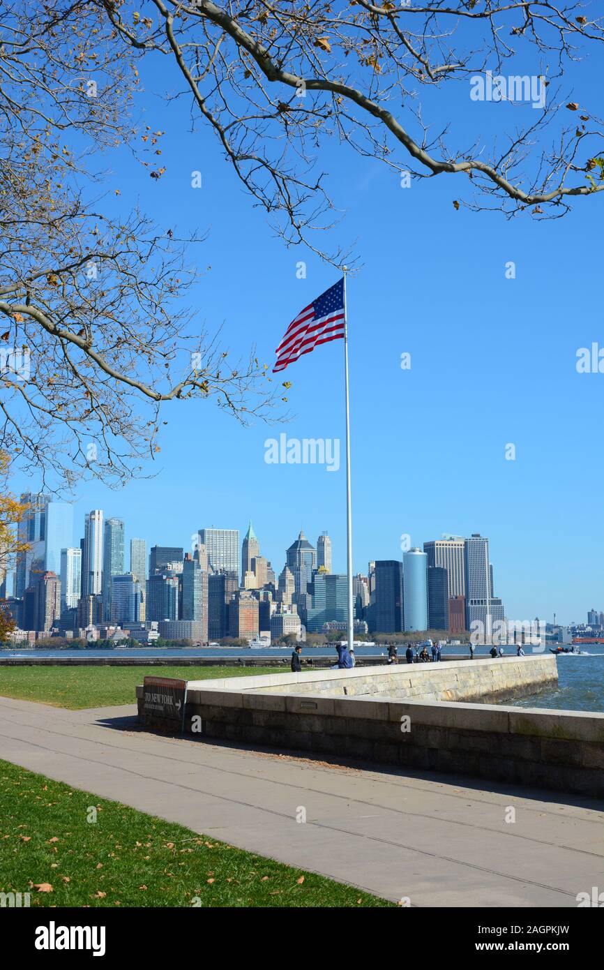 NEW YORK, NY - 04 NOV 2019: Flag on Ellis Island with Manhattan skyline ...