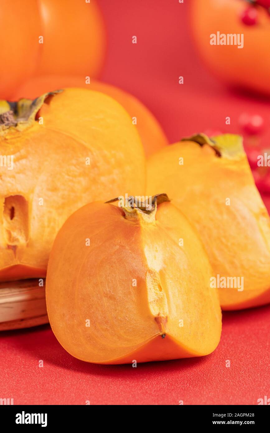 Fresh beautiful sliced sweet persimmon kaki isolated on red table ...