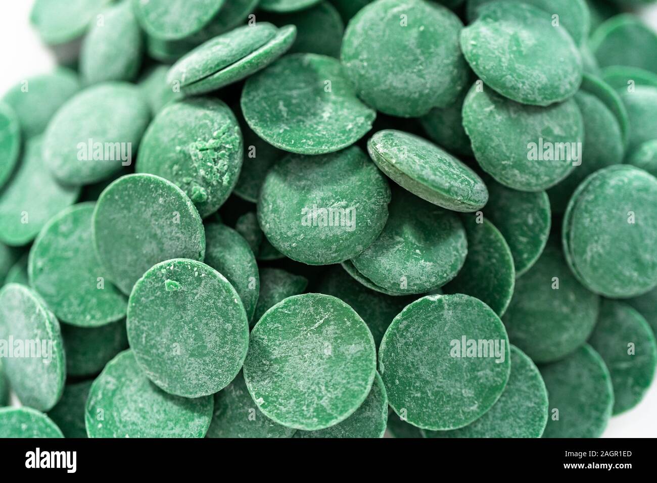 Green round chocolate chips for melting chocolate shapes on a white ...