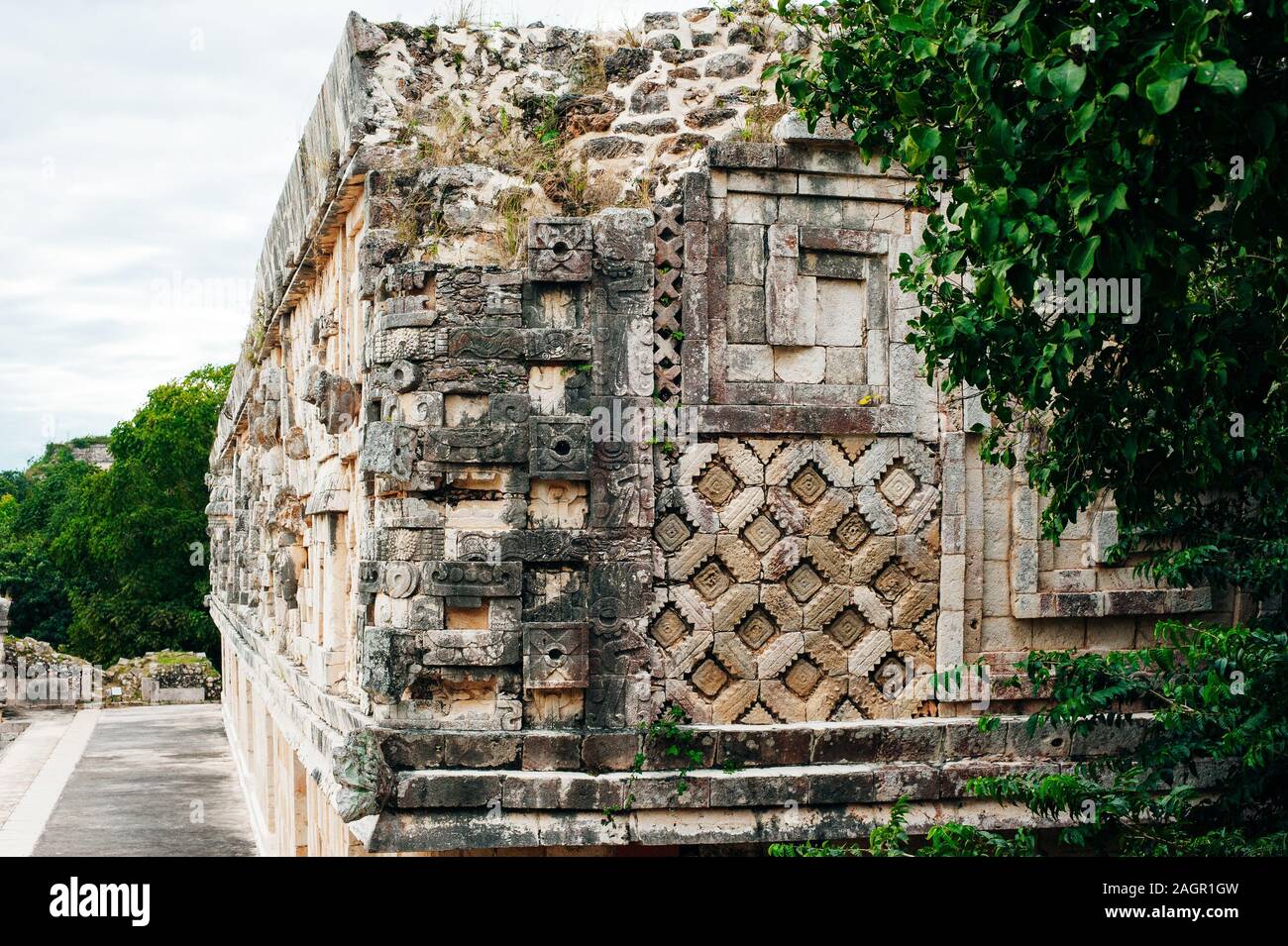 Ancient mayan wall with arches with green garden around in Uxmal ...
