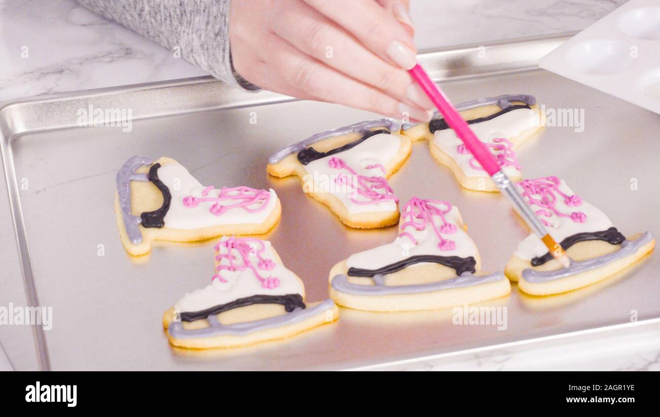 Brushing edible glitter on iced figure skate sugar cookies Stock Photo ...