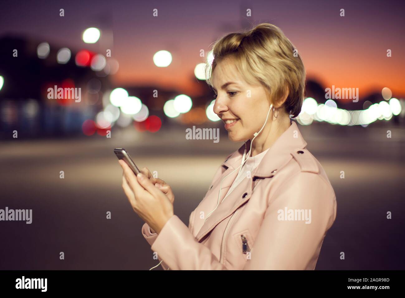 Woman using mobile phone on the street in the night time. People and ...