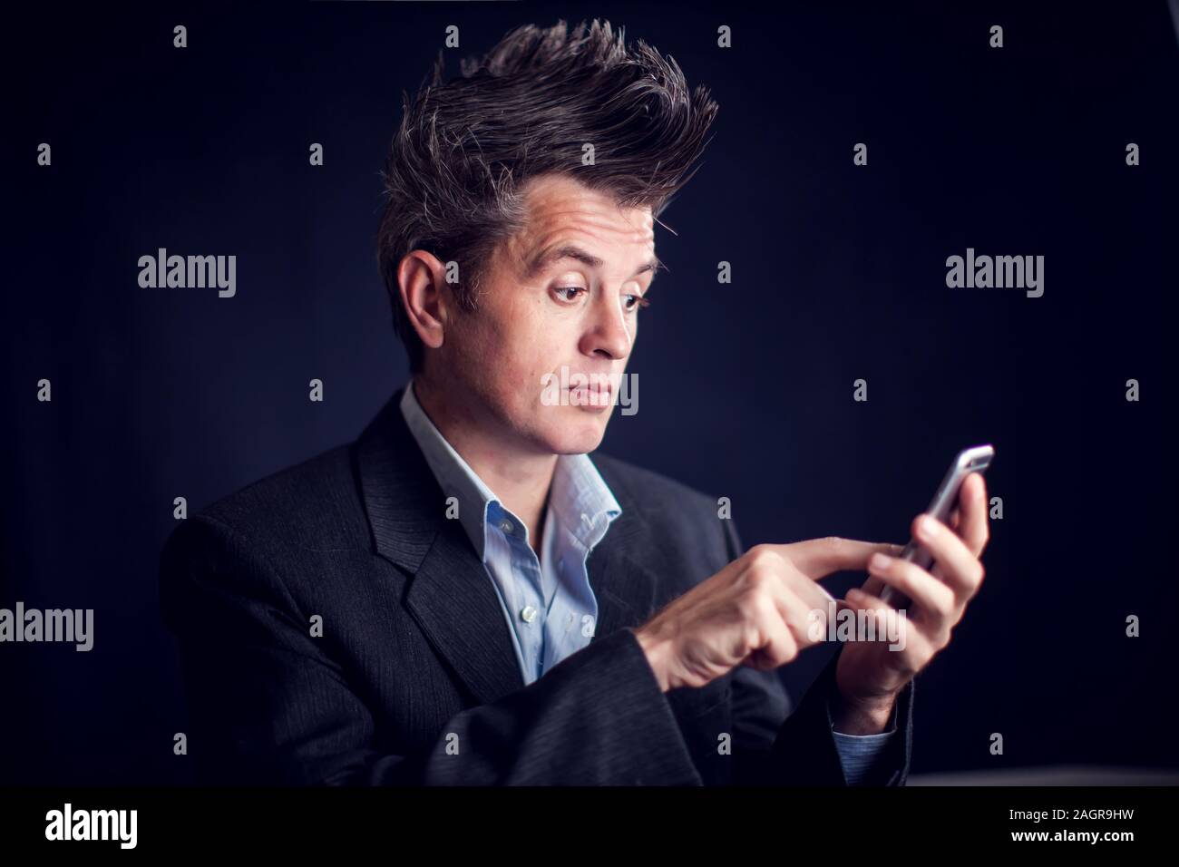 Handsome man with mohawk wearing suit using mobile phone in front of ...