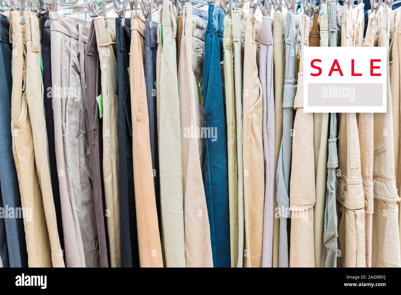 clothes hanging on a rack in a flea market stall. with sale signboard ...