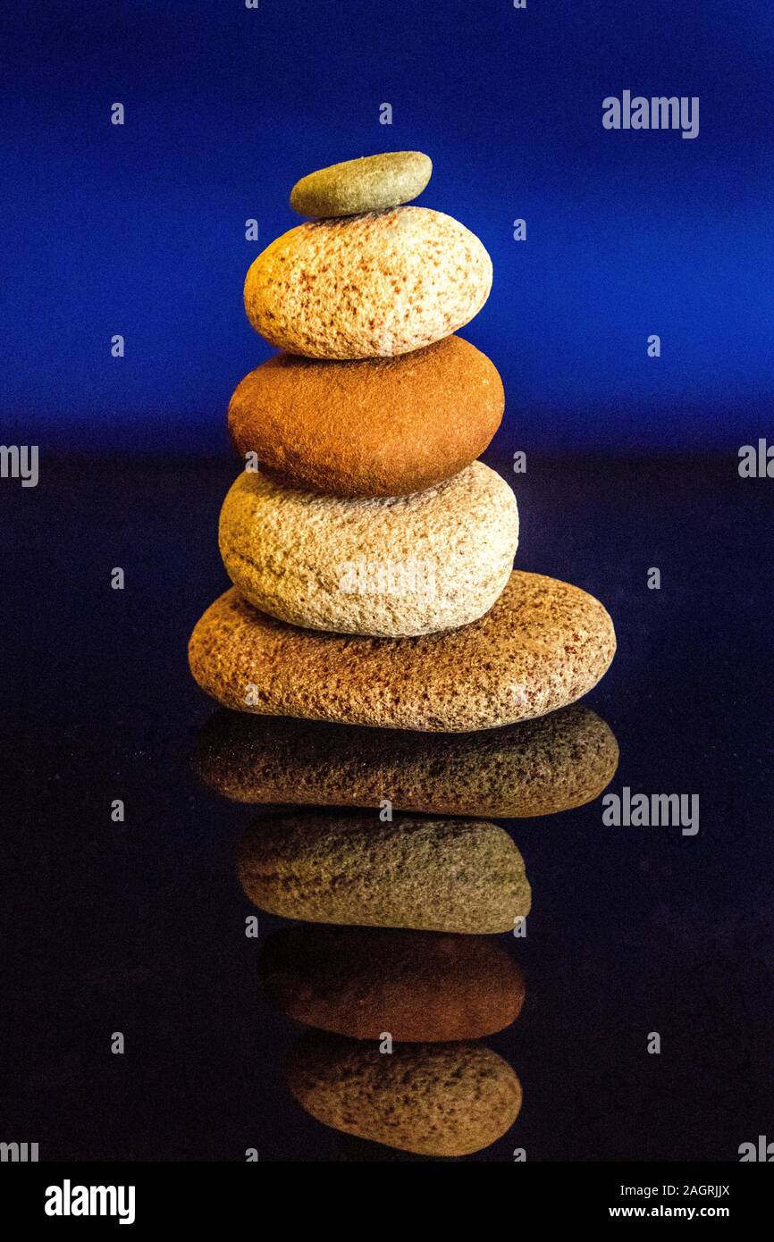 Small pebbles stacked on top of each other against a black and blue ...