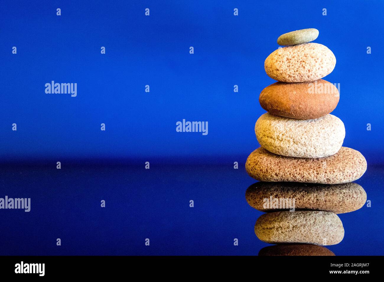 Small pebbles stacked on top of each other against a black and blue ...