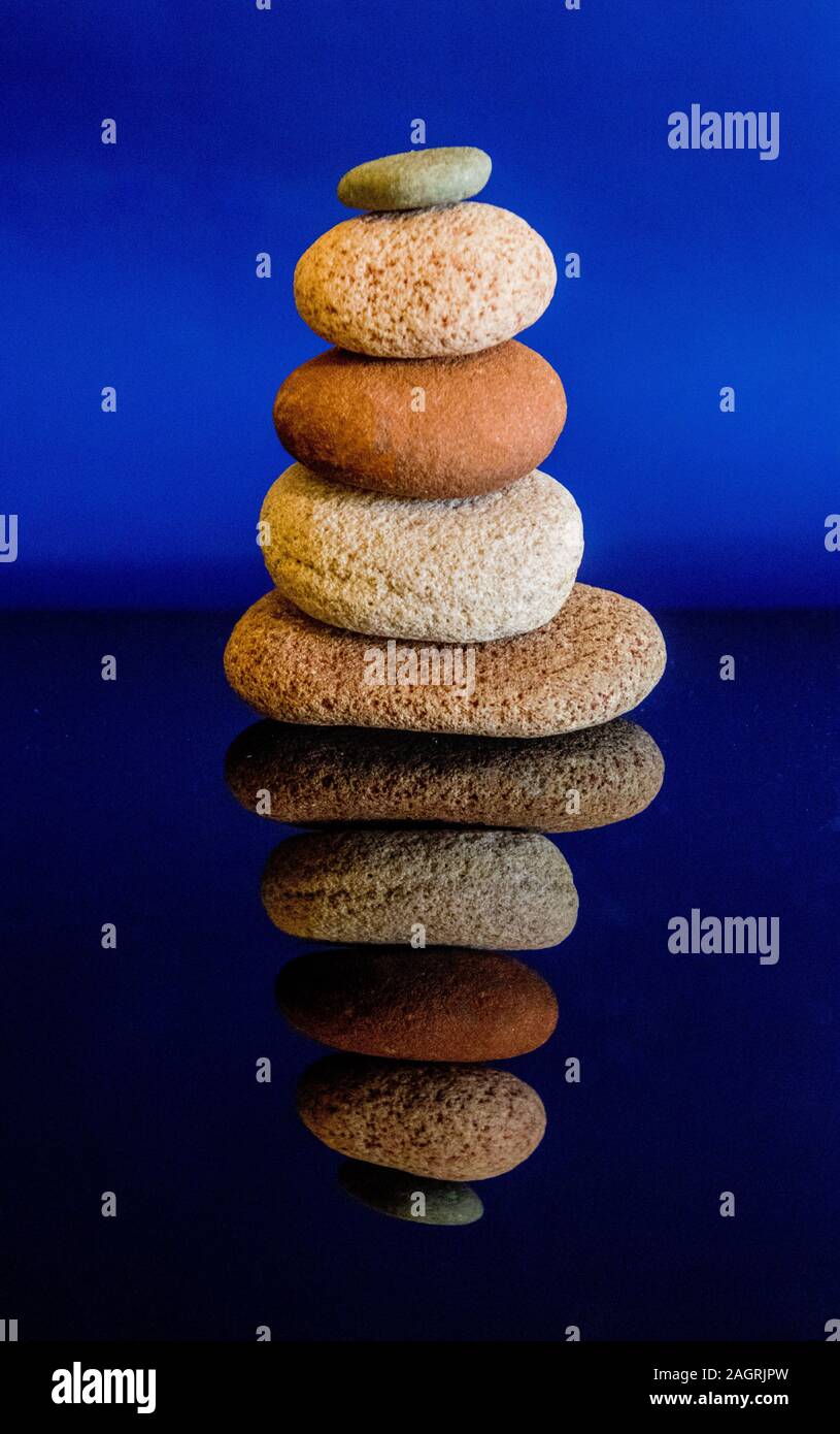 Small pebbles stacked on top of each other against a black and blue ...