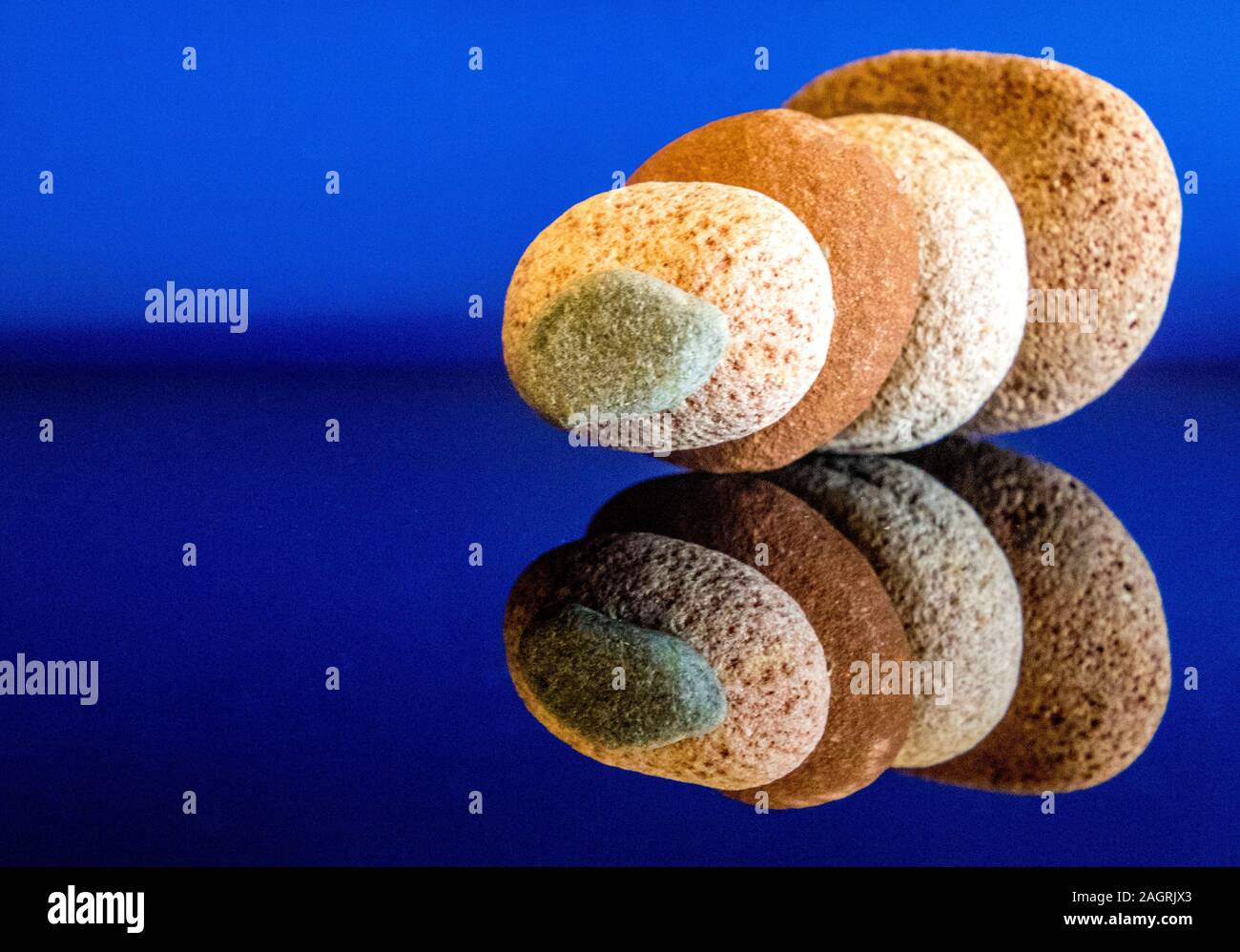 Small pebbles stacked on top of each other against a black and blue ...