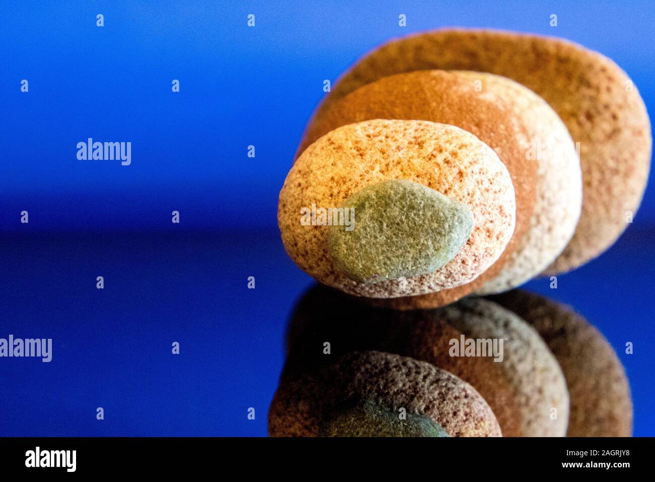 Small pebbles stacked on top of each other against a black and blue ...
