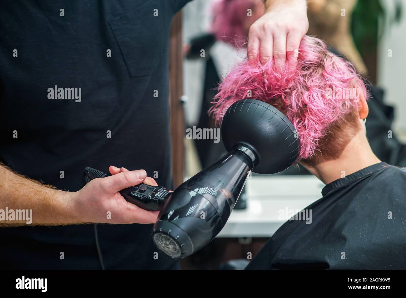 Happy female stylist blow drying senior woman's hair in salon Stock ...
