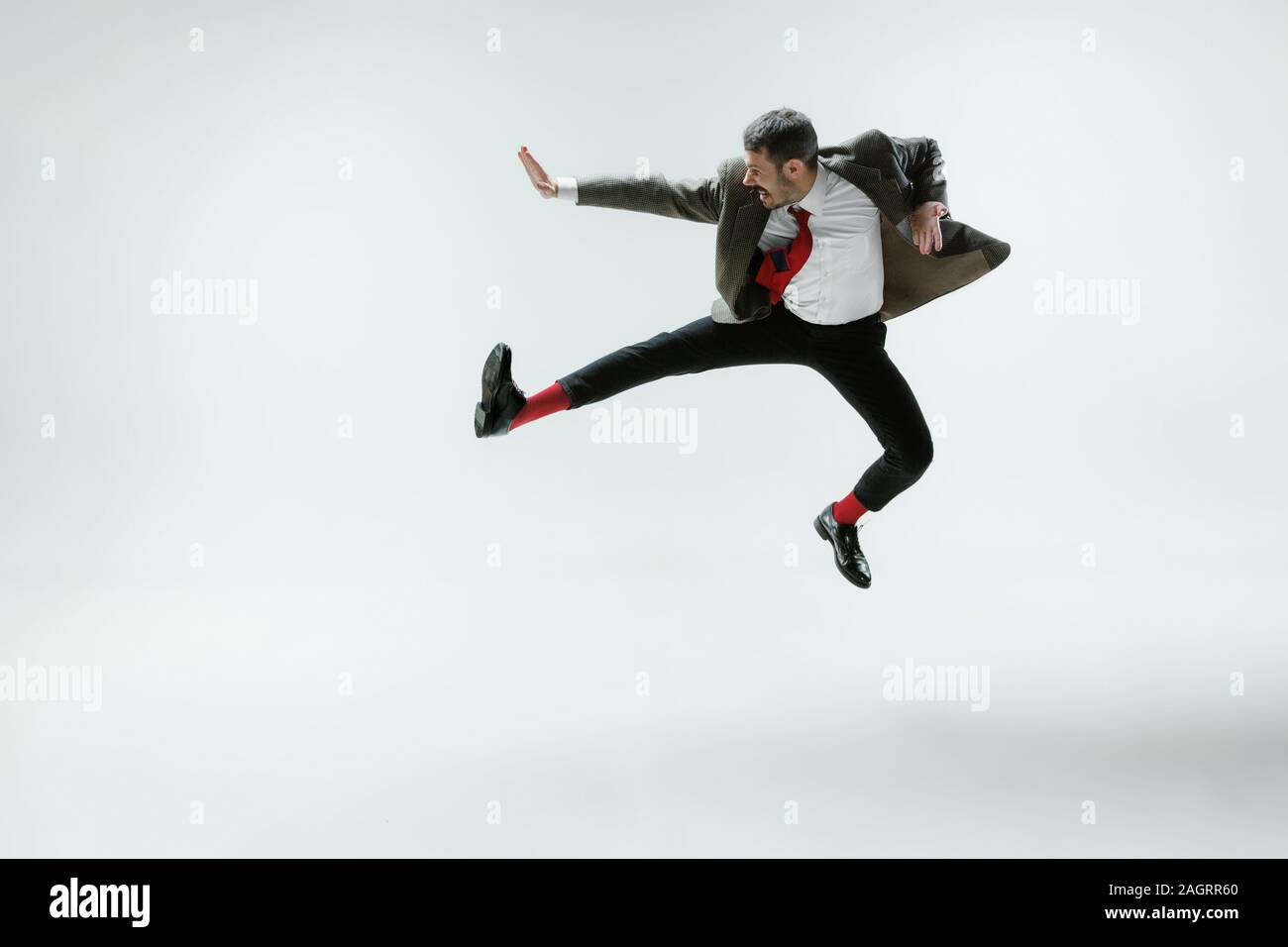 Young caucasian man moving flexible on white studio background. Male ...