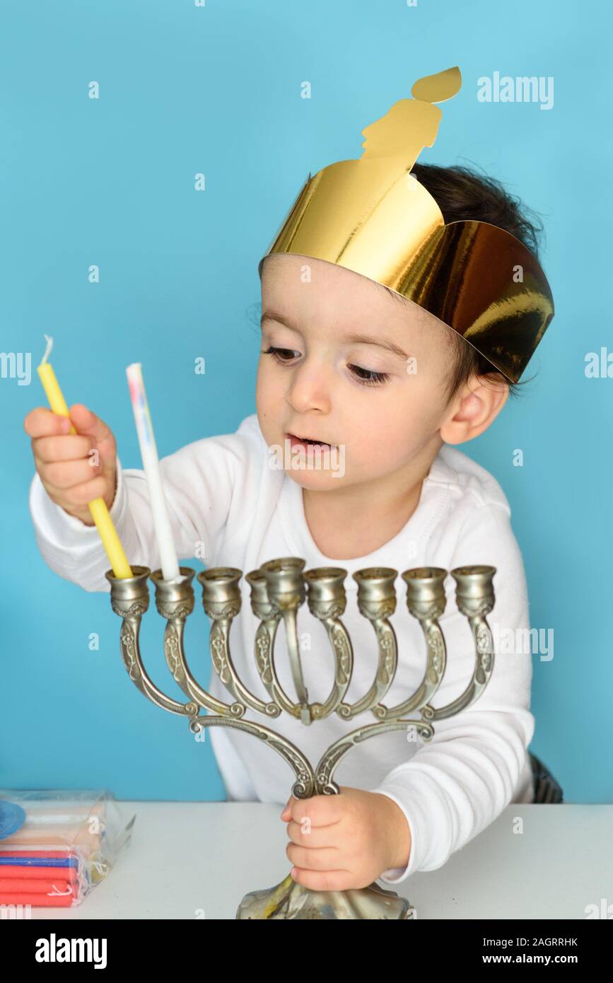Kid celebrating Hanukkah Israel holiday. Little jewish boy puts candles ...