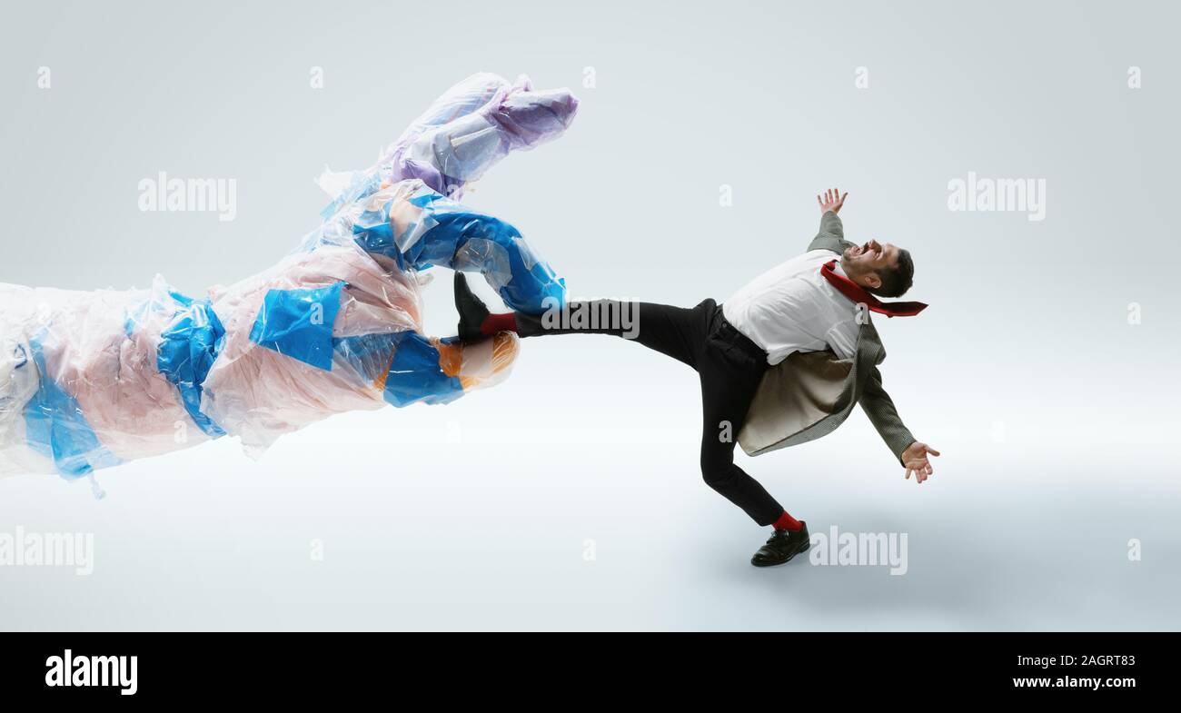 Young caucasian man avoiding big plastic hand on white studio ...