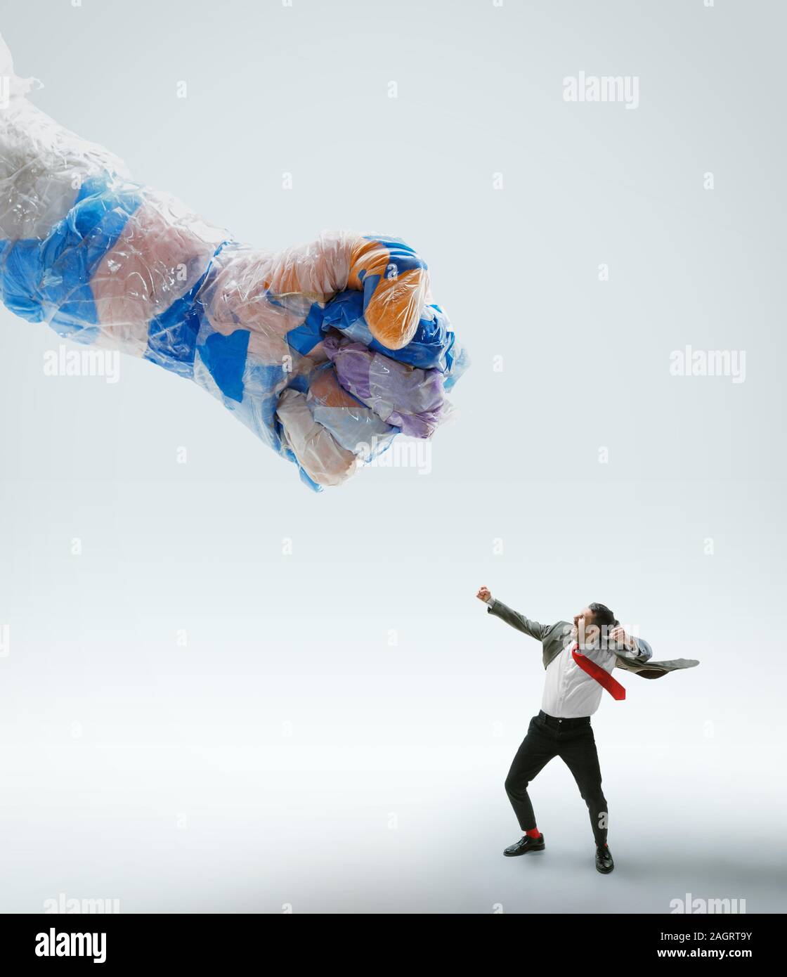 Young caucasian man avoiding big plastic hand on white studio ...