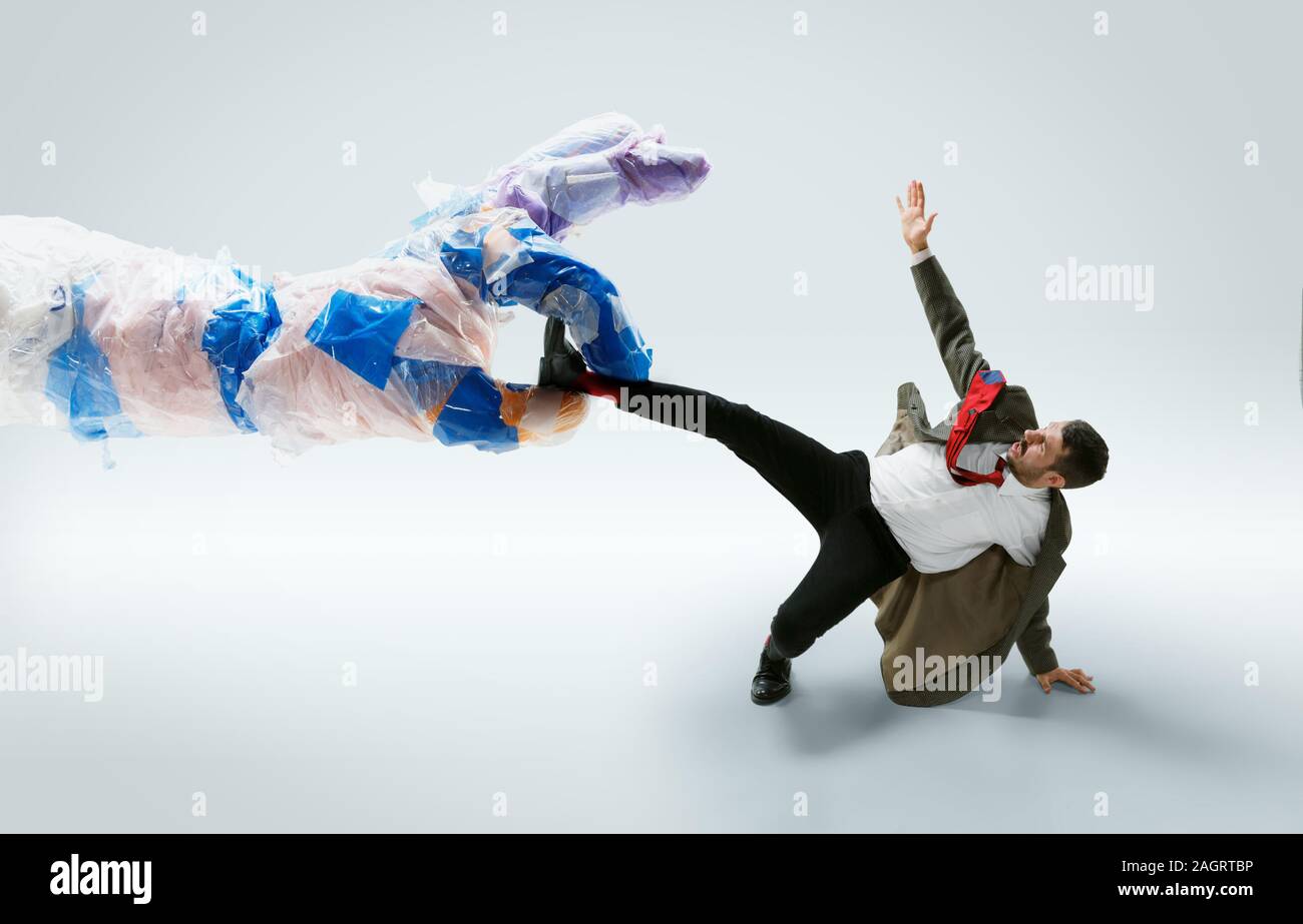 Young caucasian man avoiding big plastic hand on white studio ...