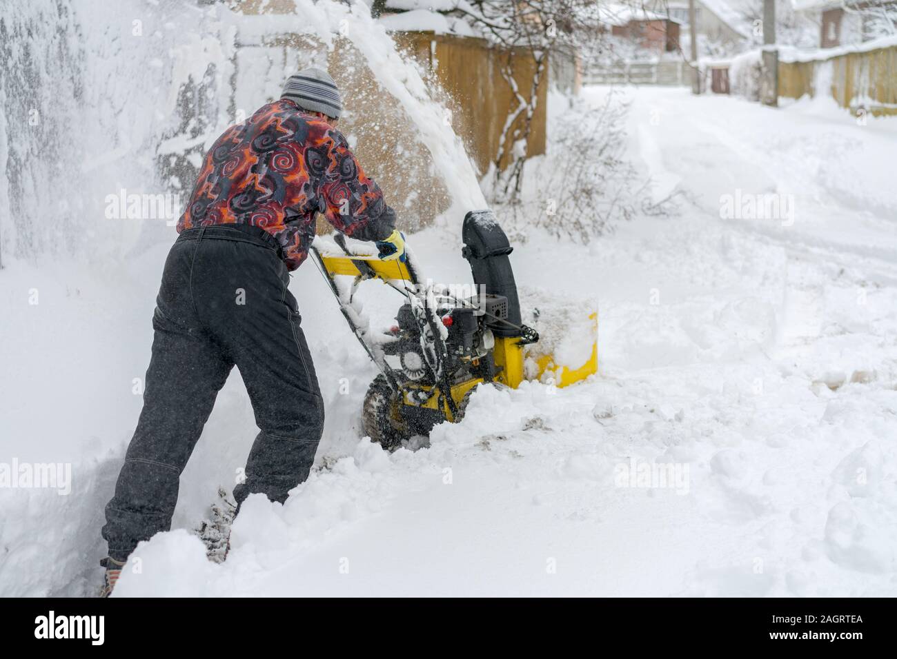 man operating snow blower to remove snow on driveway. Man using a ...