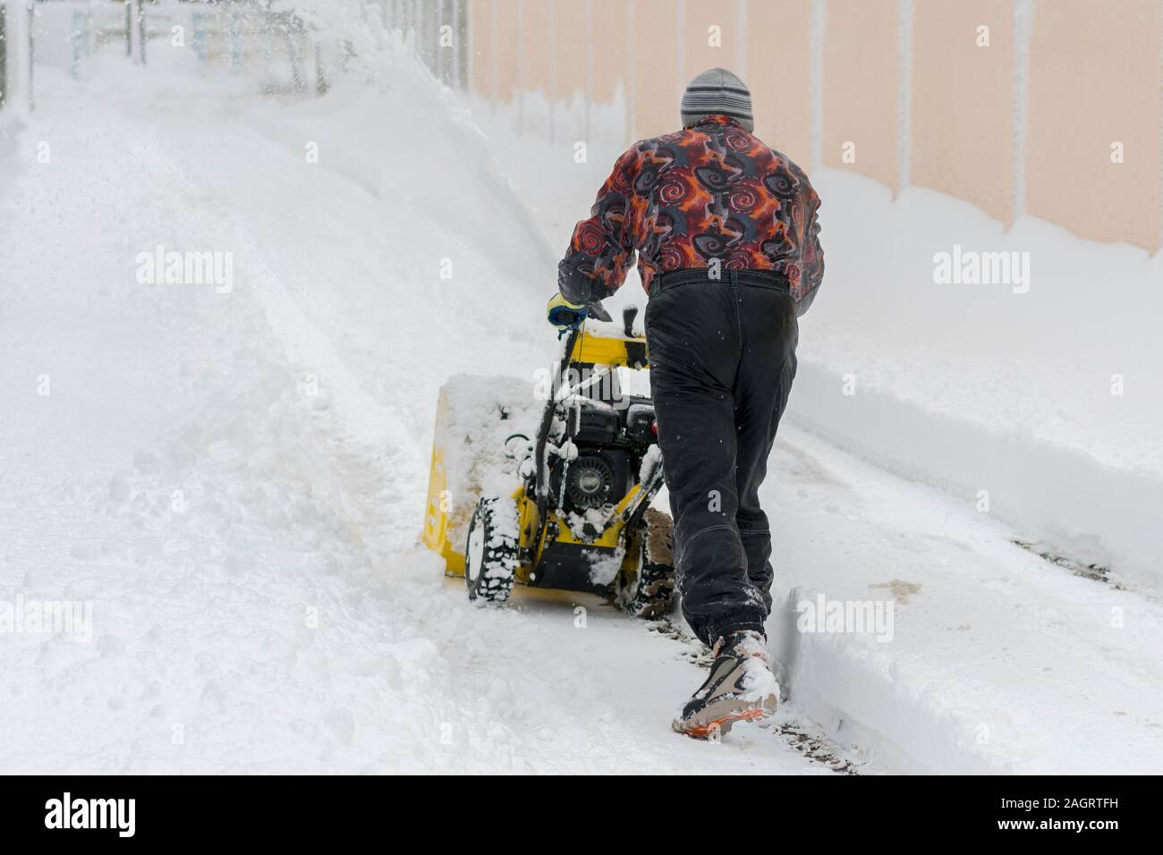 man operating snow blower to remove snow on driveway. Man using a ...