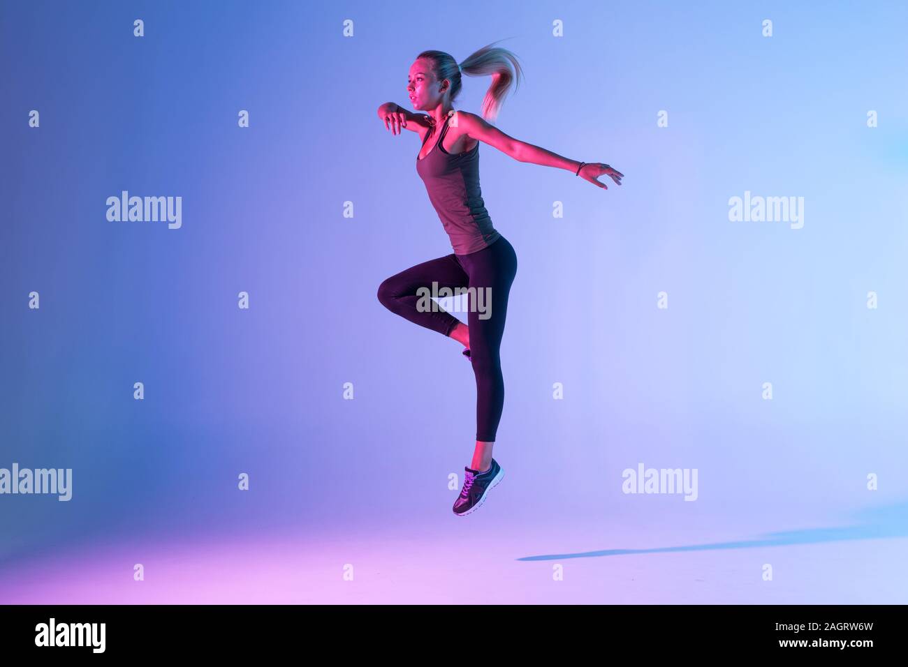 Handsome woman with perfect body jumping against colorful trendy ...