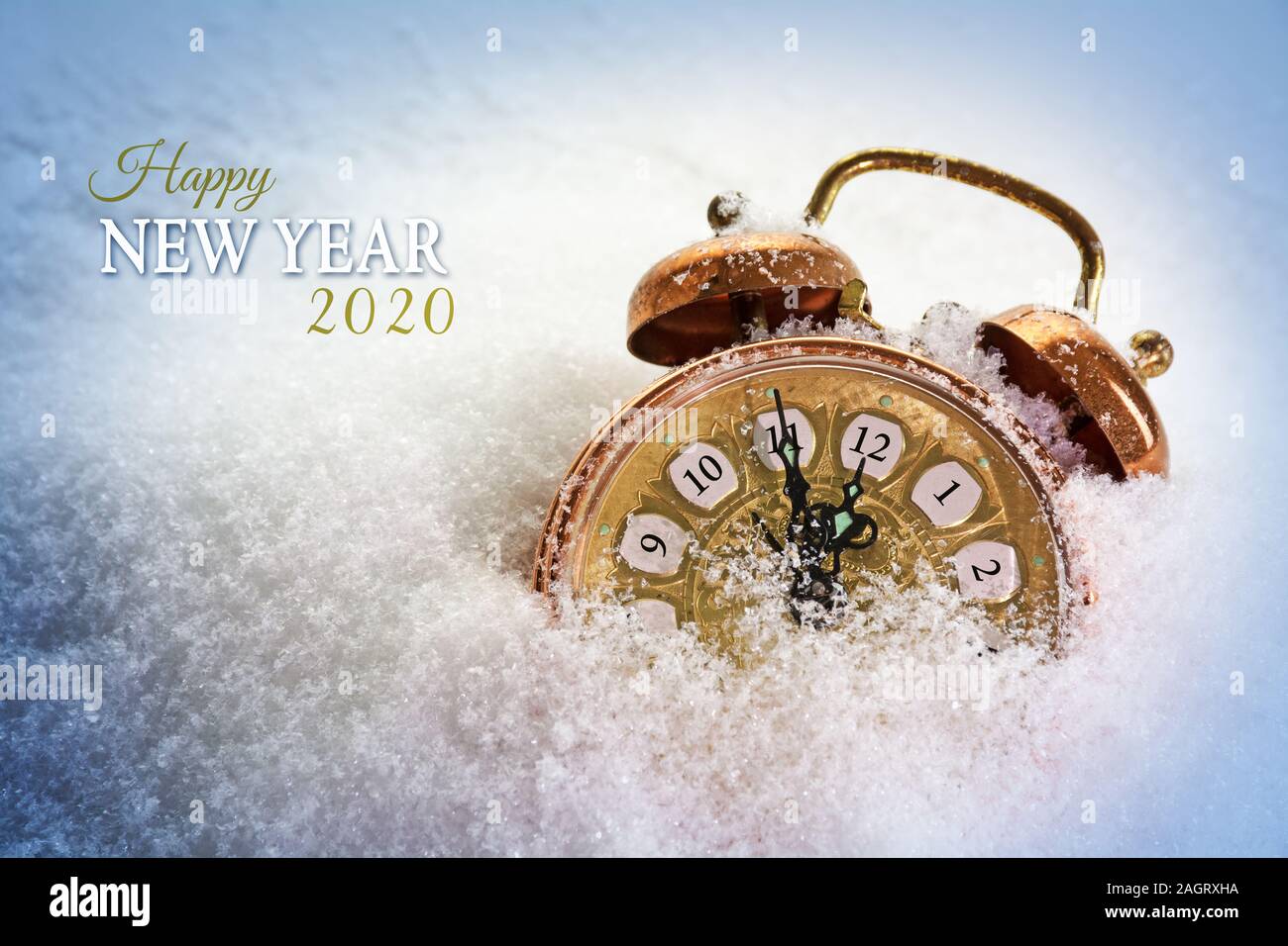 Happy New Year 2020 text and a vintage alarm clock in the snow shows ...