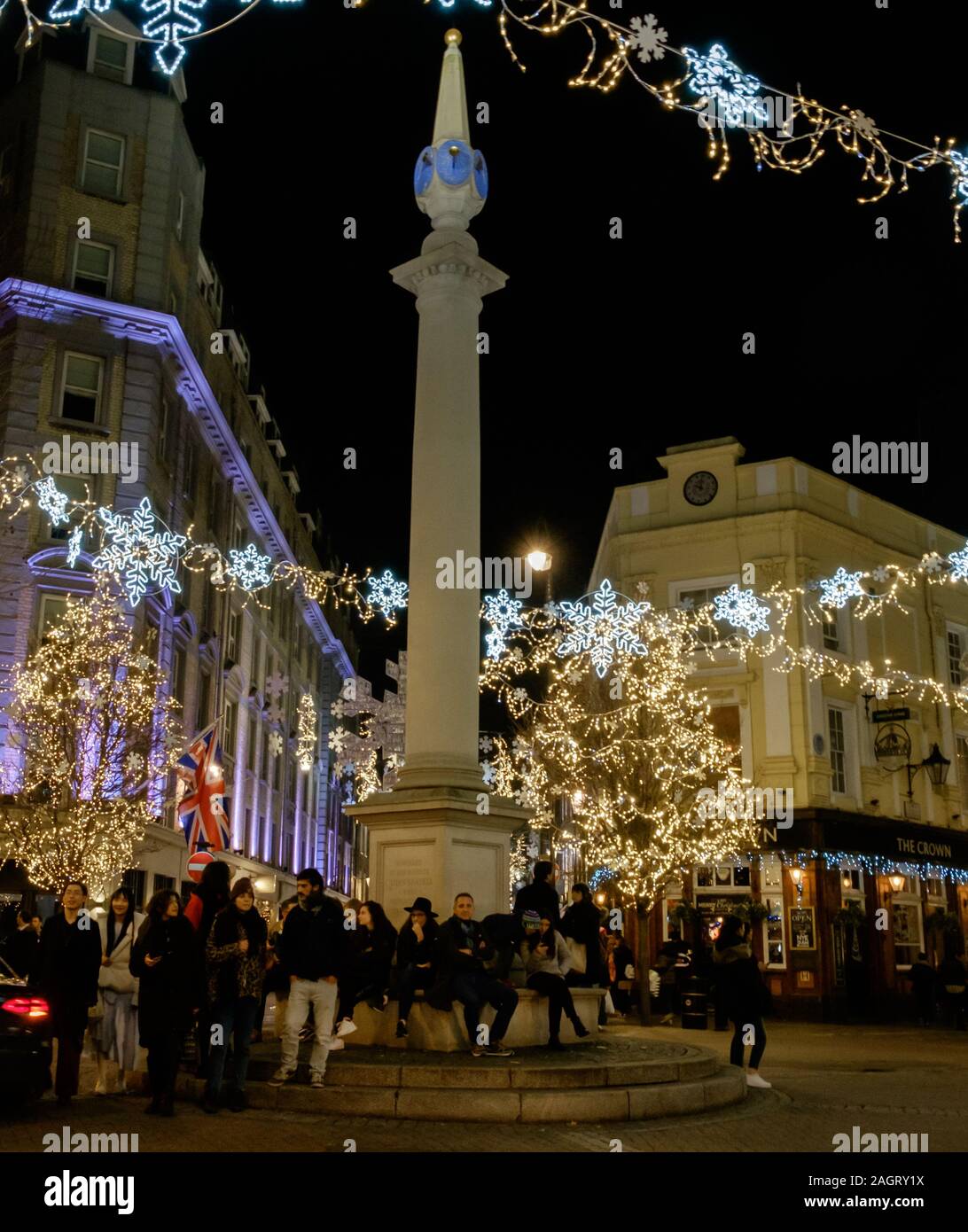 People sit on the sundial monument at Seven Dials with Christmas Lights ...