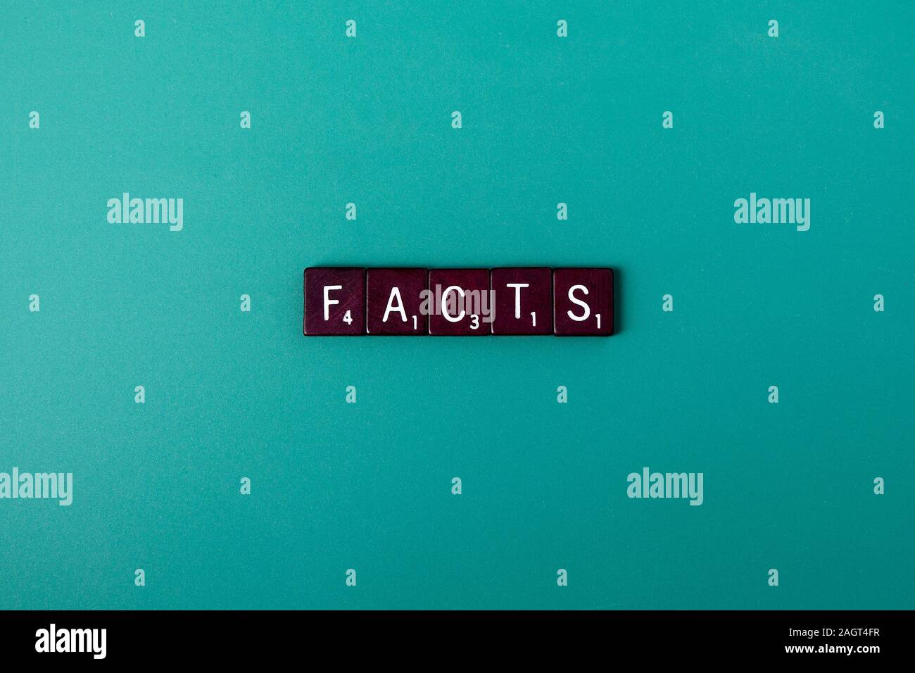 The word facts spelled out in wooden block letters on a blue green ...