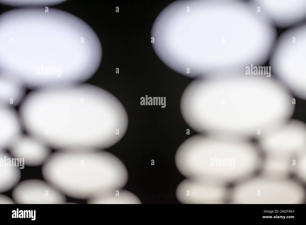 blurred photo of white lights on a black background. dark spot in the ...