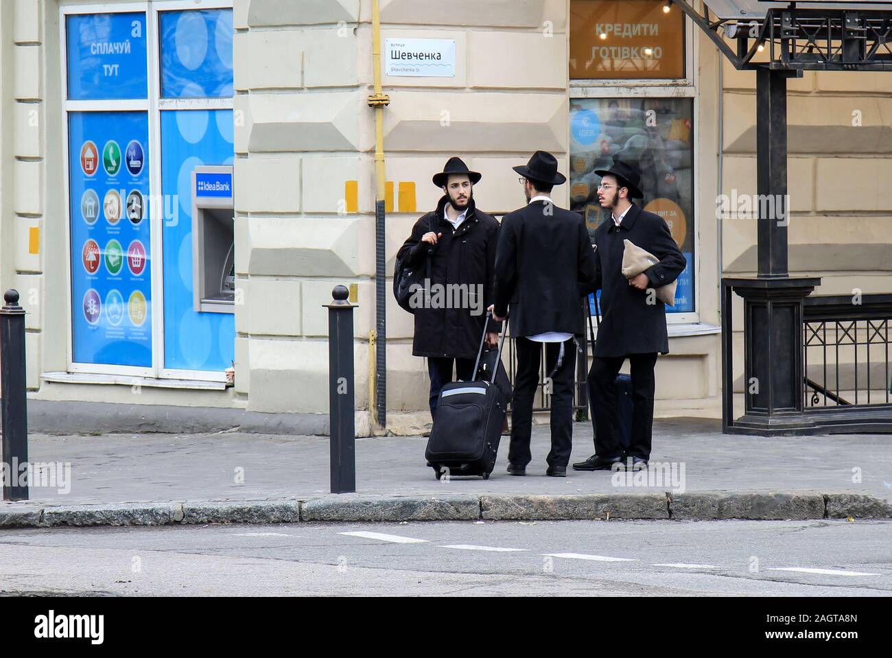 3 Jewish boys, Hasidic Jews, in black clothes and hats with suitcases ...