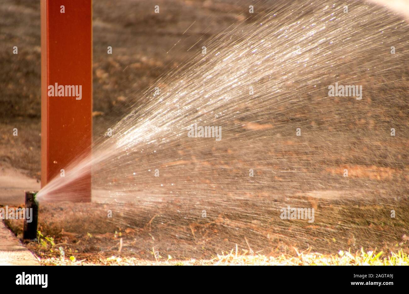 A water spray system jets out water to an area of grass to keep it ...