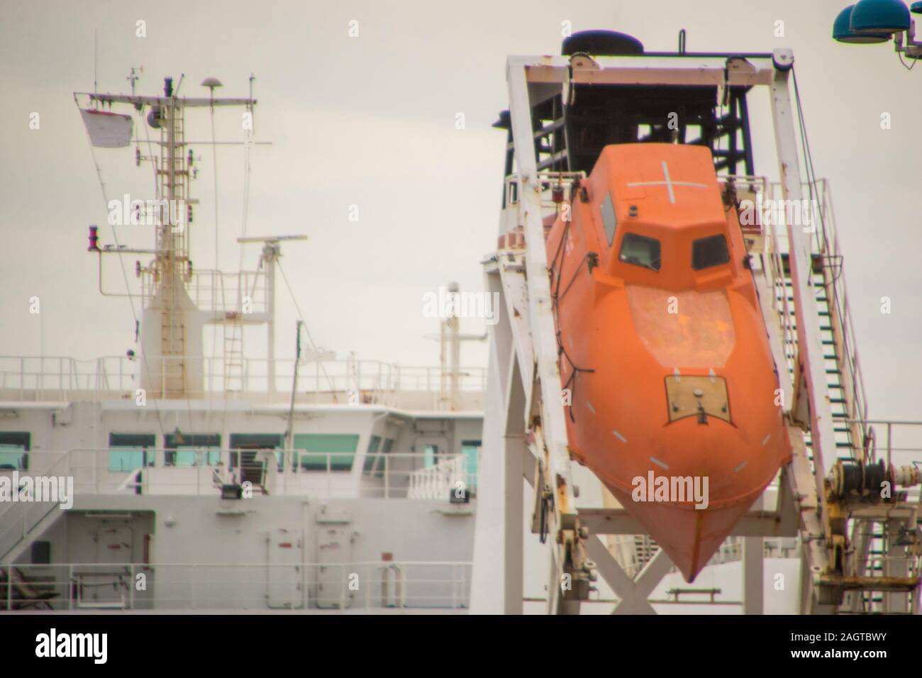 A large orange safety boat primed on the back of a large ship Stock ...