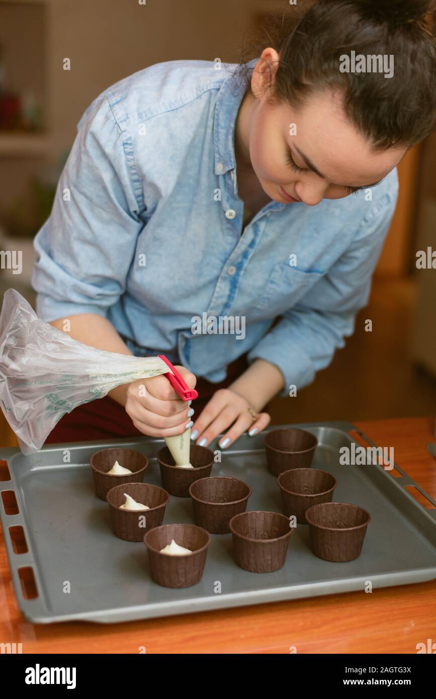 attractive girl making cupcakes, closeup side view photo. woman learns ...
