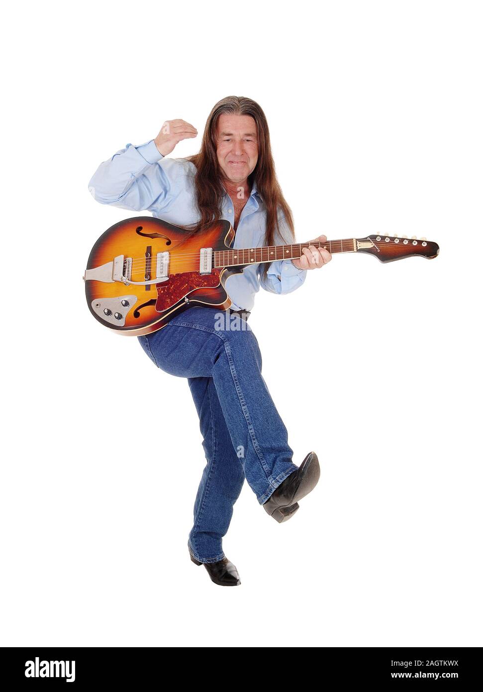 A happy musician dancing with his guitar with his long brunette hair ...