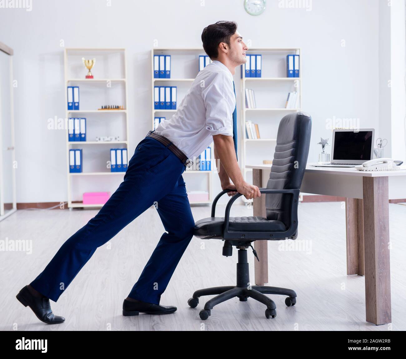 The young businessman doing sports stretching at workplace Stock Photo ...
