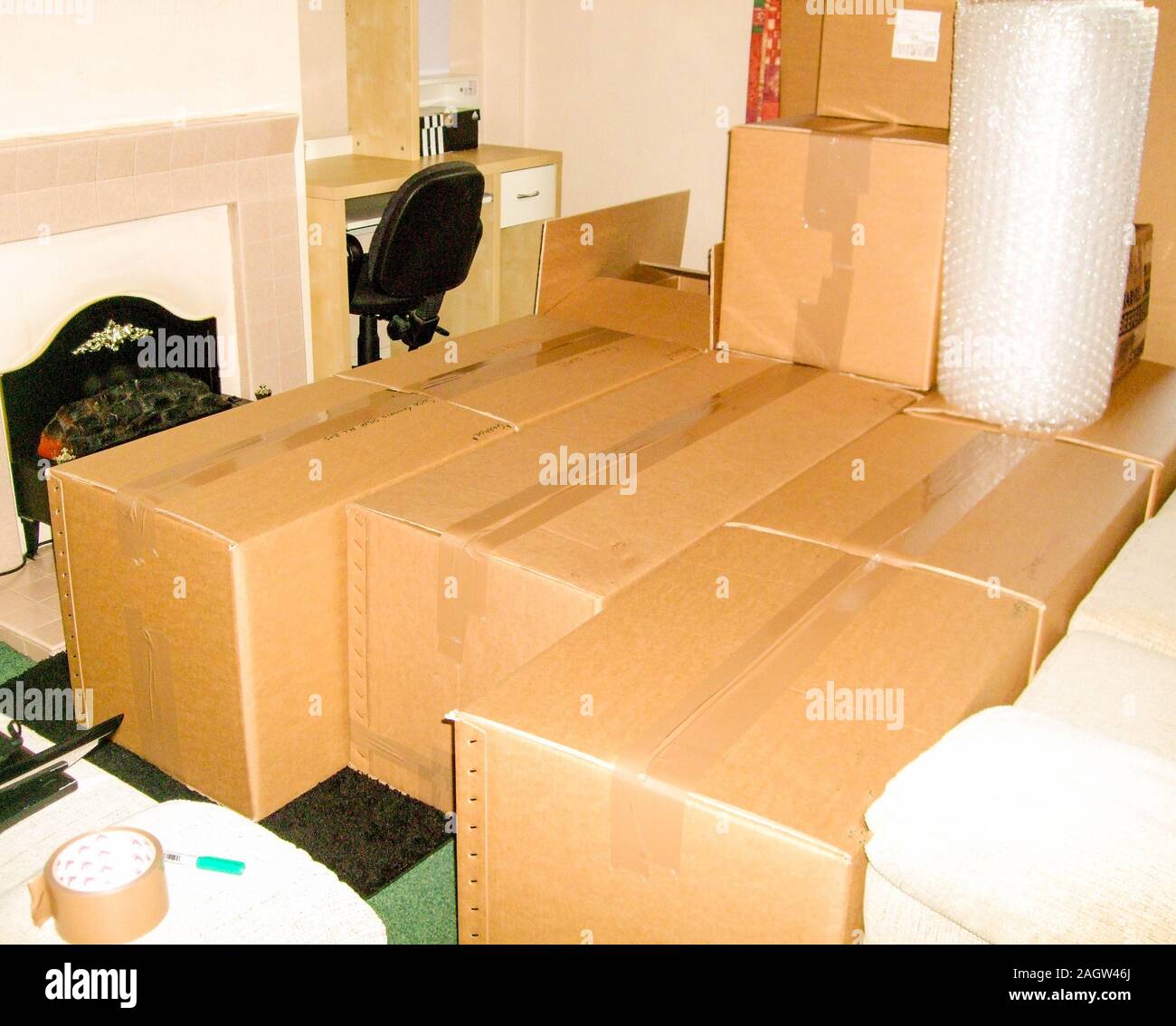 A stack of packed boxes within a small household room, awaiting to be ...